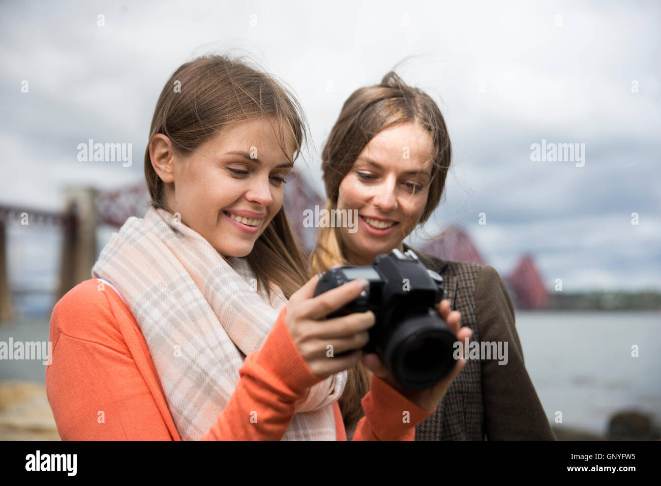 Portrait of two happy female friends taking photos with a DSLR ...