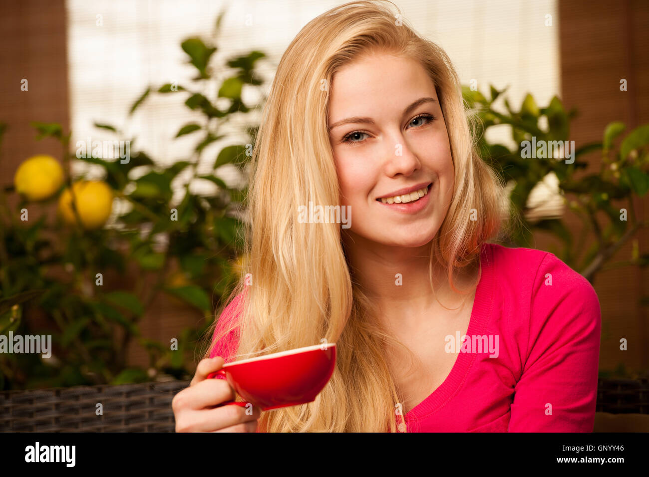 Woman comfortable sitting on sofa surrounded with lemon tree and other ...
