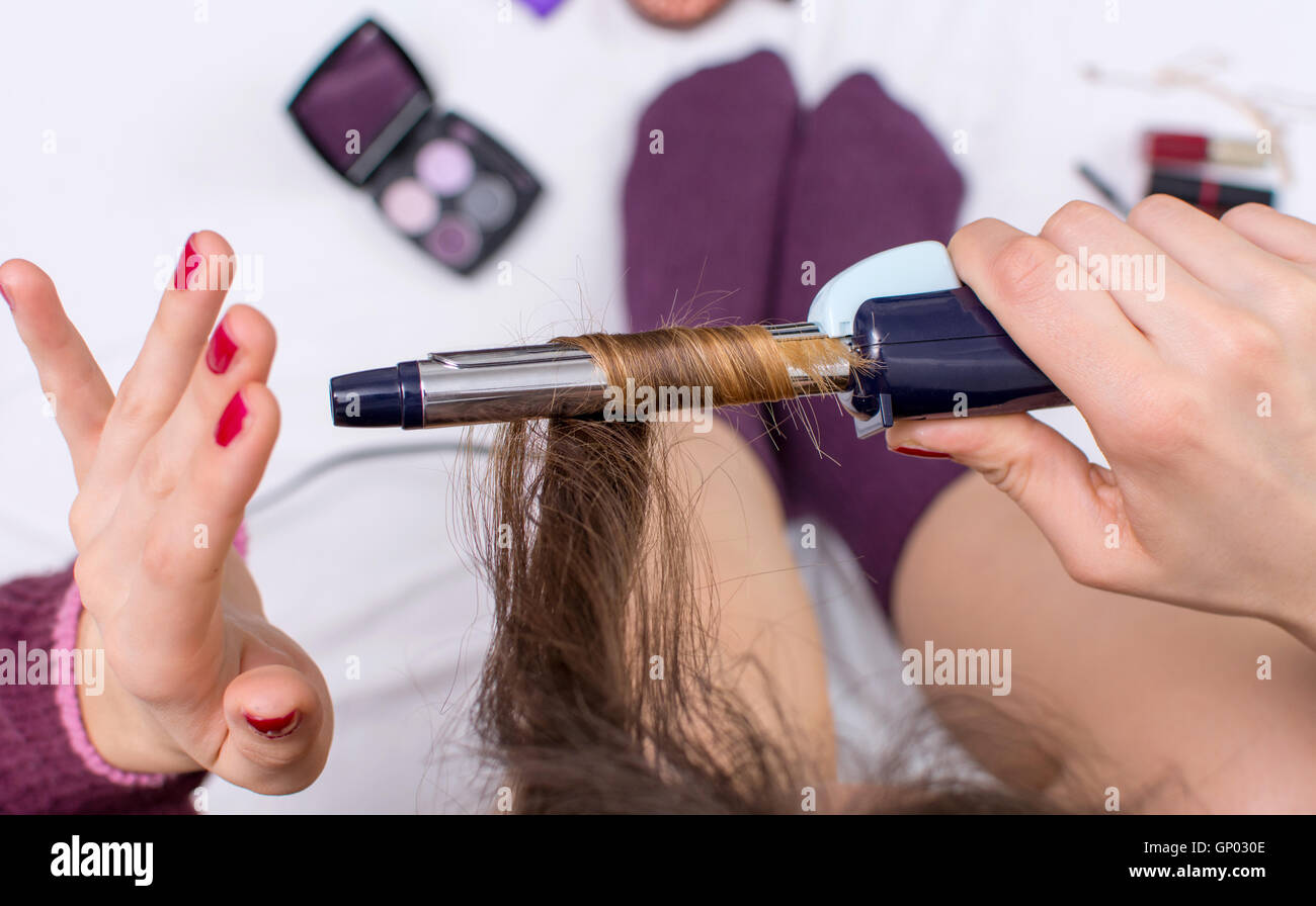 Woman using curling iron on her hair point of view Stock Photo - Alamy