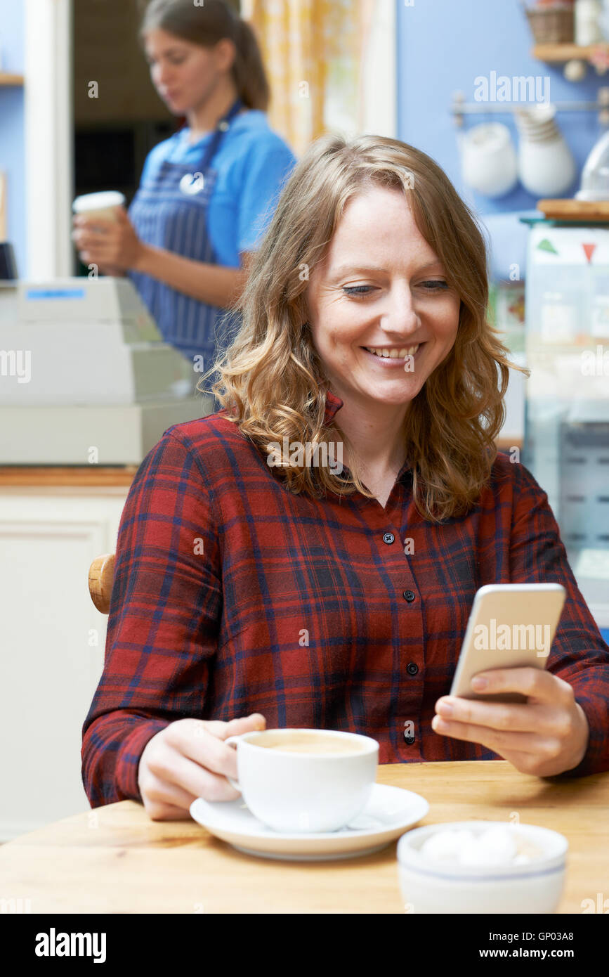 Woman In Coffee Shop Reading Text Message On Mobile Phone Stock Photo ...
