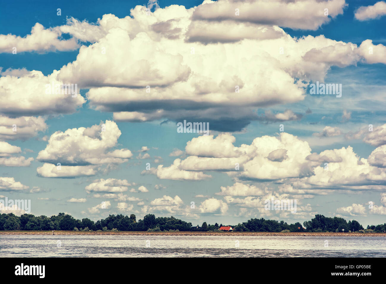 Waterfront with trees and house and blue sky with big clouds. Danube ...