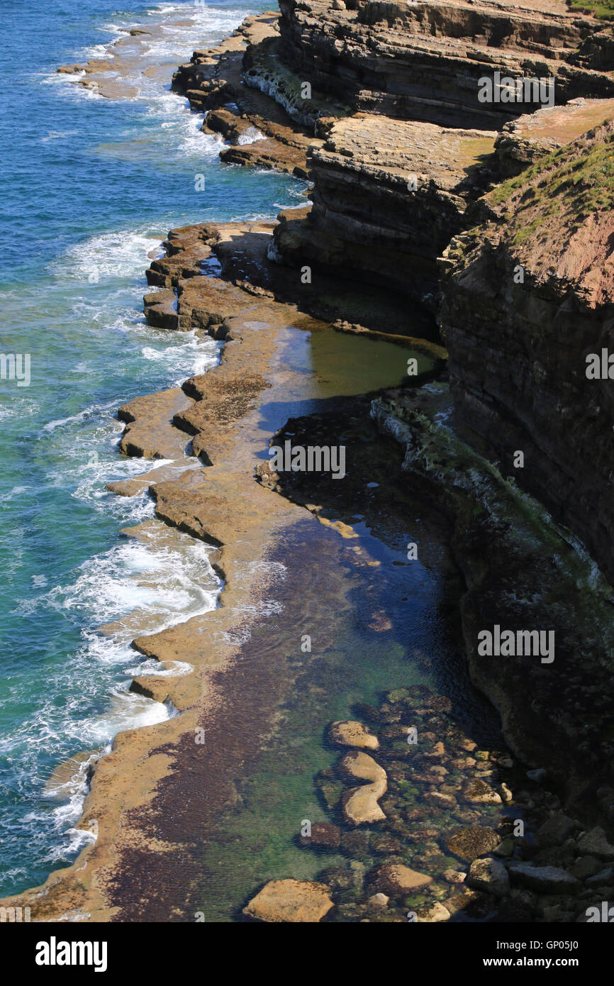 Sea under rocky cliffs, rocky platform exposed at low tide Stock Photo ...