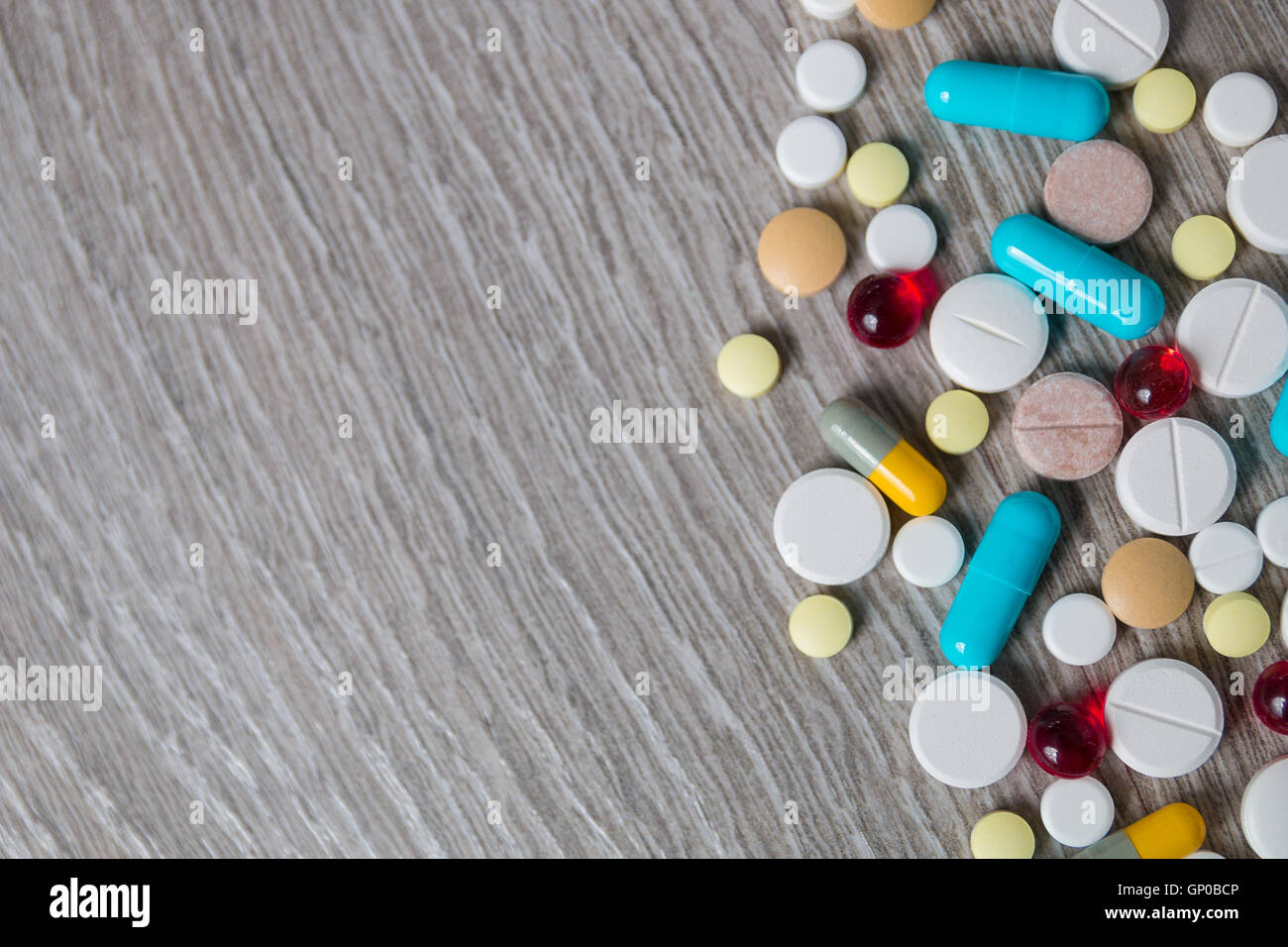 A lot of colorful medication and pills from above on grey wooden ...