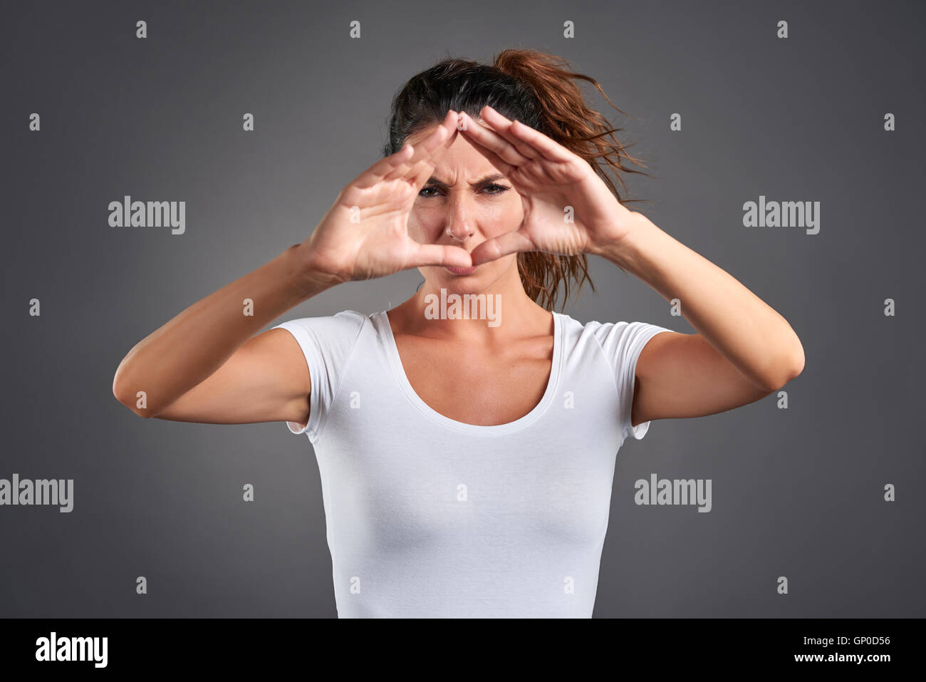 An angry young woman shaping a triangle with her hands and looking ...