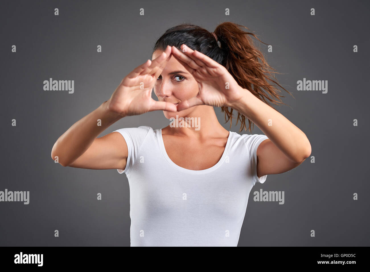 A beautiful young woman shaping a triangle with her hands and looking ...