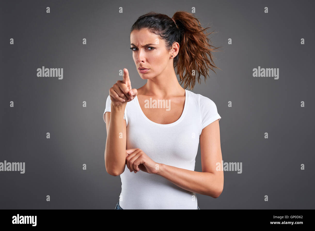 A beautiful young woman feeling suspicious and pointing in to the ...