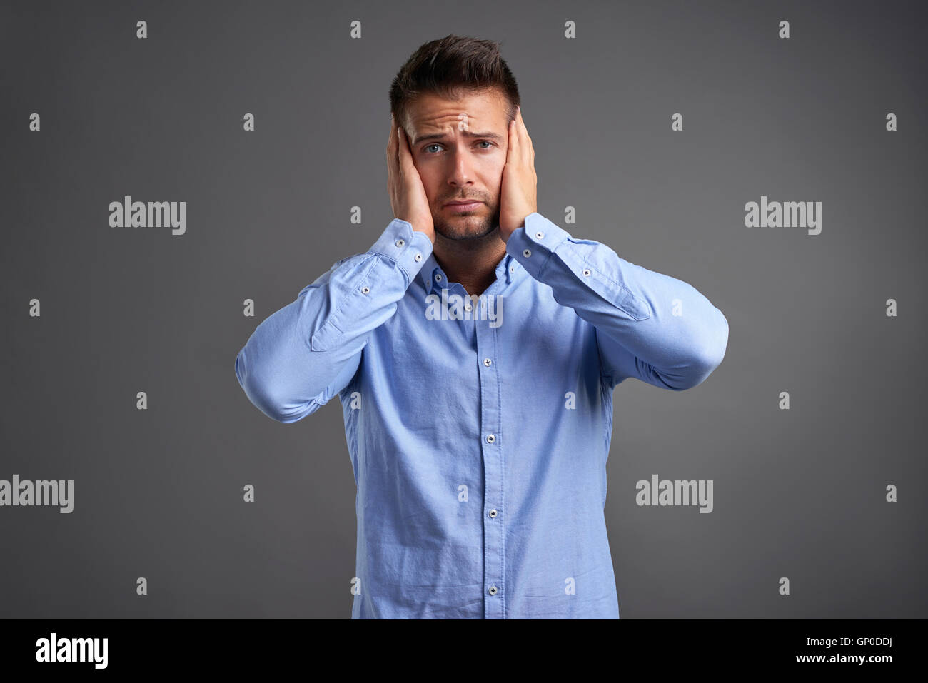 A handsome young man feeling stressed and grabbing his head in a studio ...