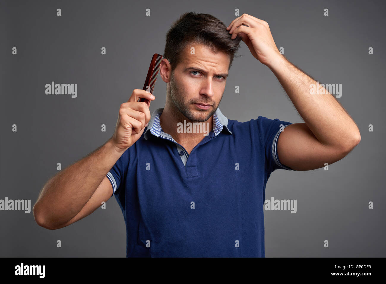 A serious handsome young man combing his hair Stock Photo - Alamy