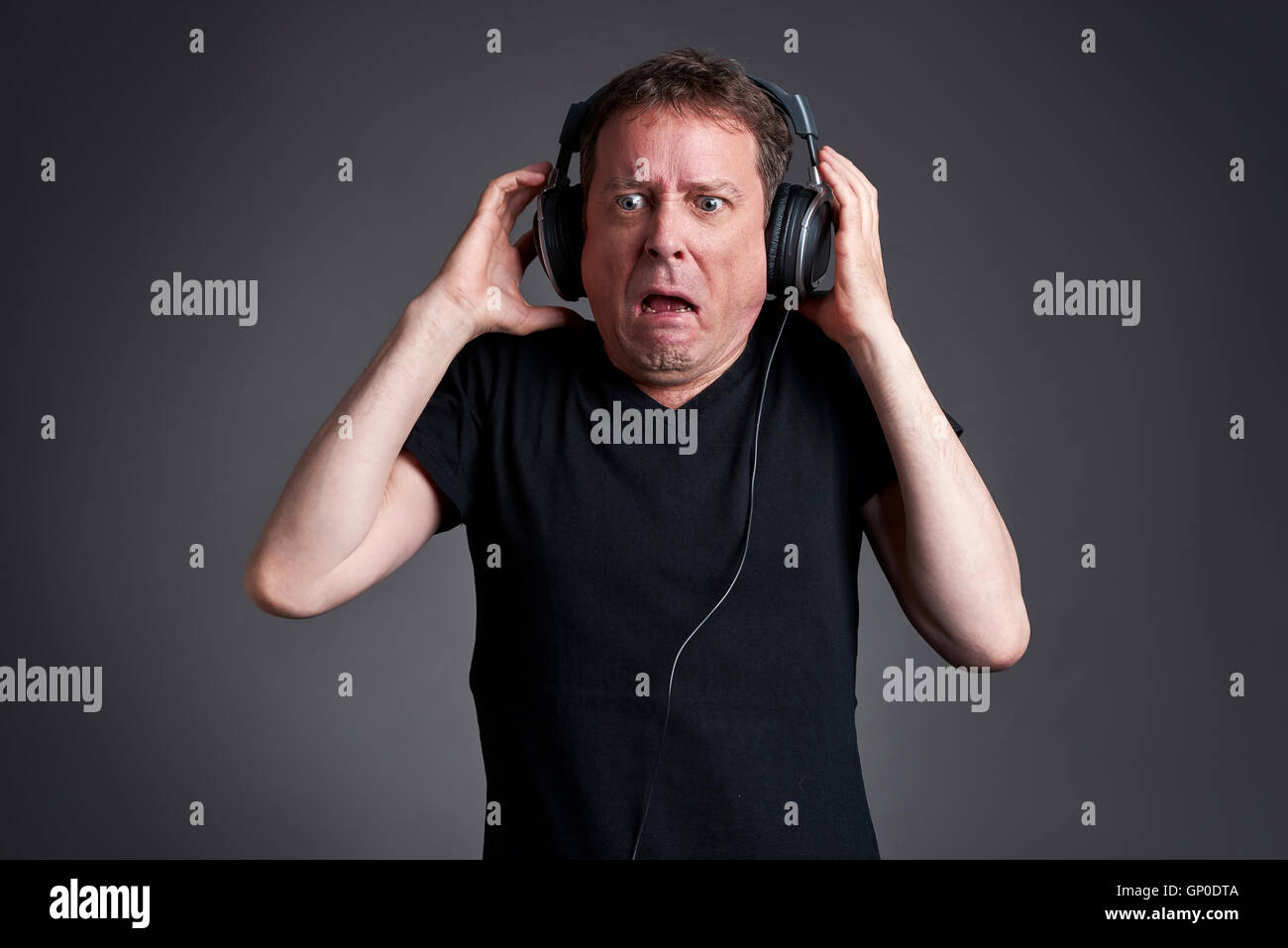 A middle age man grabbing the headphone on his ears while suffering ...