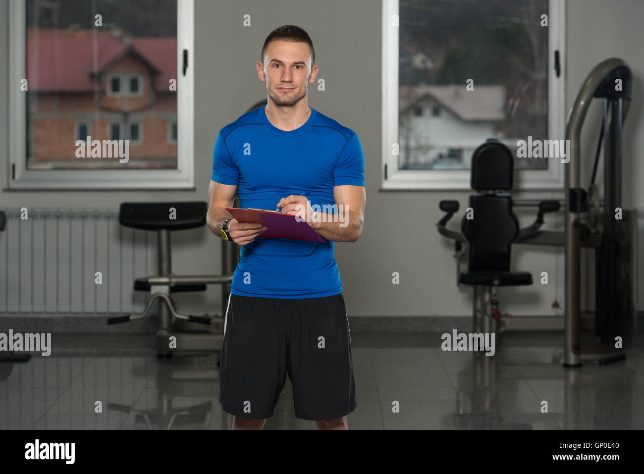 Personal Trainer In Sports Outfit Takes Notes On Clipboard In A Fitness ...