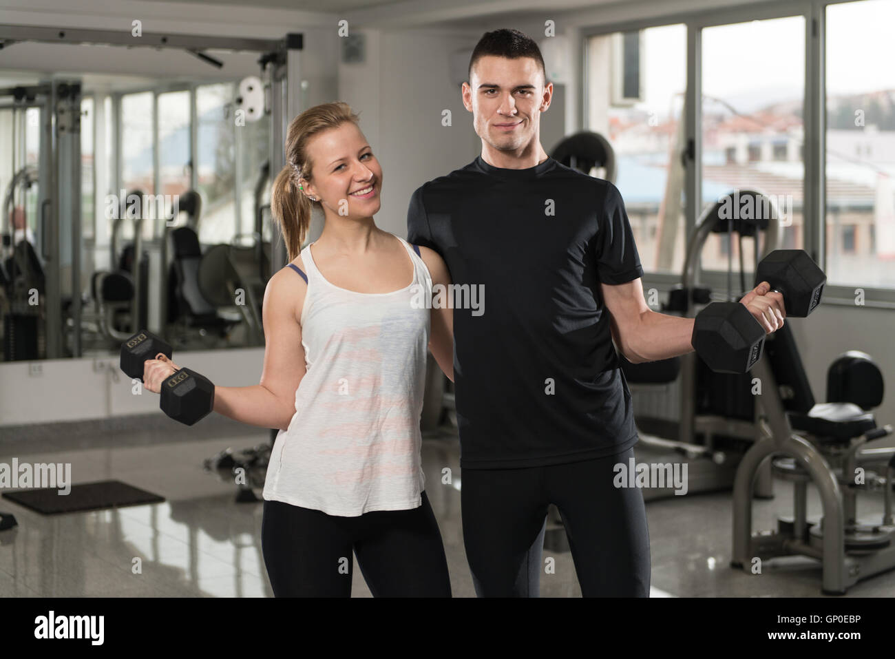 Portrait Of Fit Couple Together Training Biceps With Dumbbells In A Gym ...