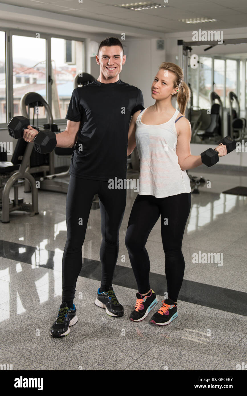 Portrait Of Fit Couple Together Training Biceps With Dumbbells In A Gym ...