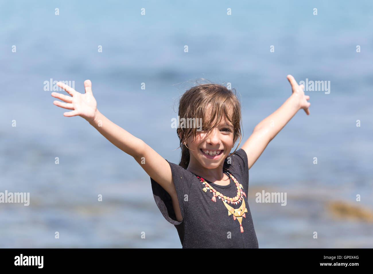 Girl with arms raised and smiling face Stock Photo - Alamy