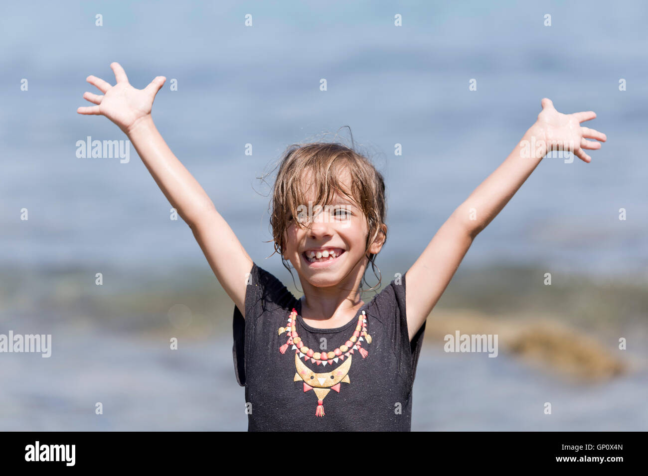 Girl with arms raised and smiling face Stock Photo - Alamy