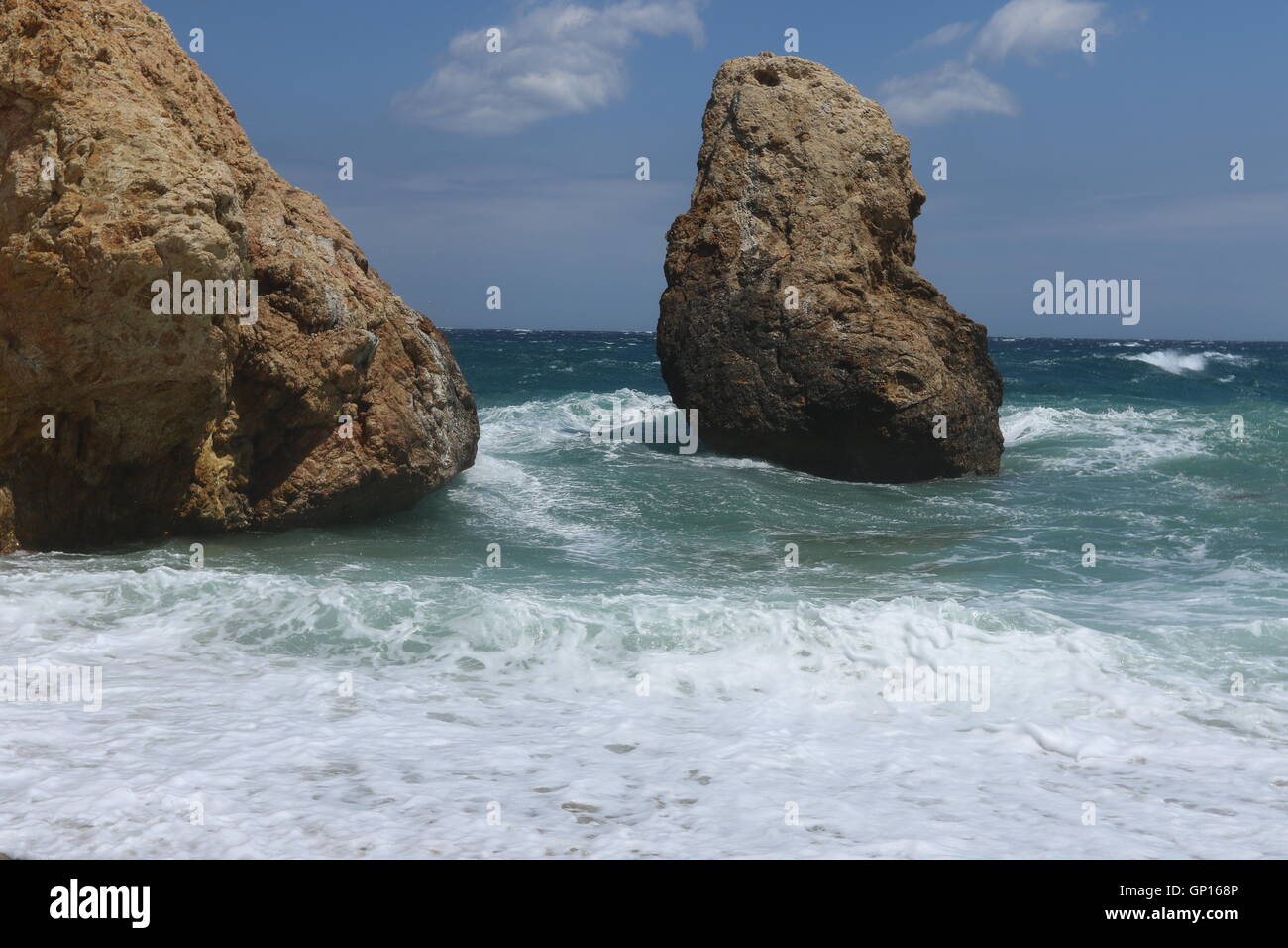 A wave is rolling onto a beach among high rocks, at Potistika, near the ...