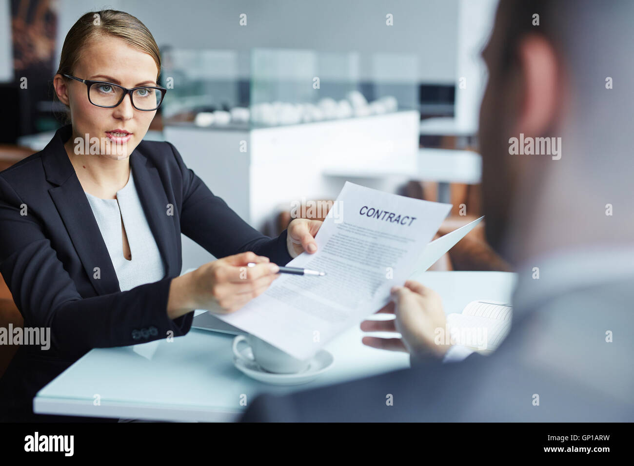 Young woman showing contract to sign to her collague Stock Photo - Alamy
