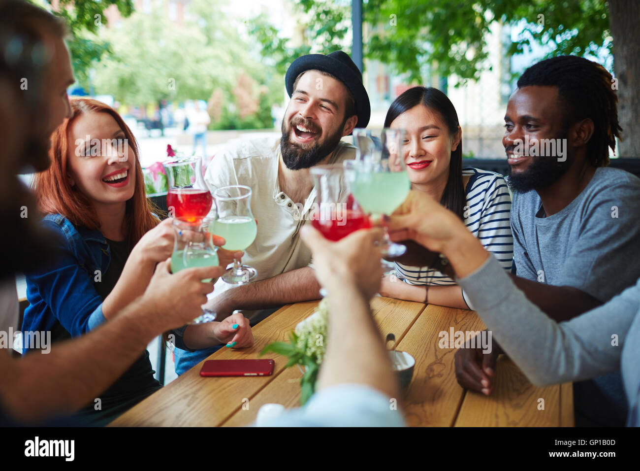 Friendly young people toasting in outdoor cafe Stock Photo - Alamy