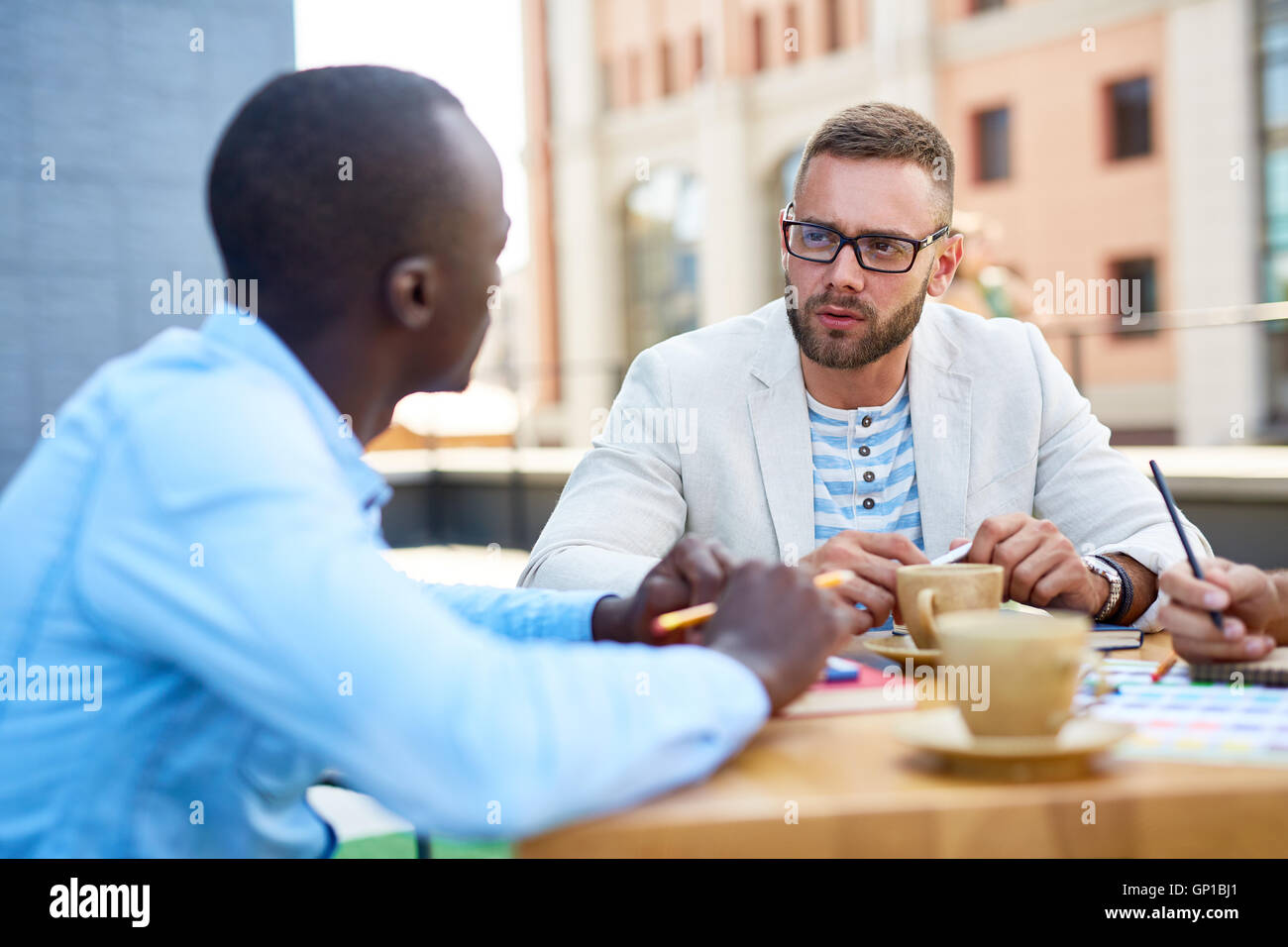 Two multi-ethnic businessmen having working conversation Stock Photo ...
