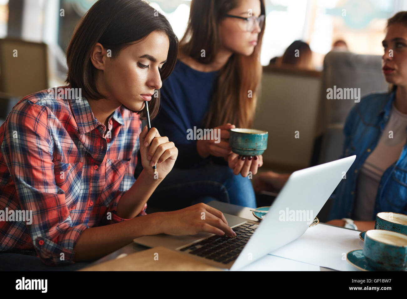 Pensive girl networking on background of her friends Stock Photo - Alamy