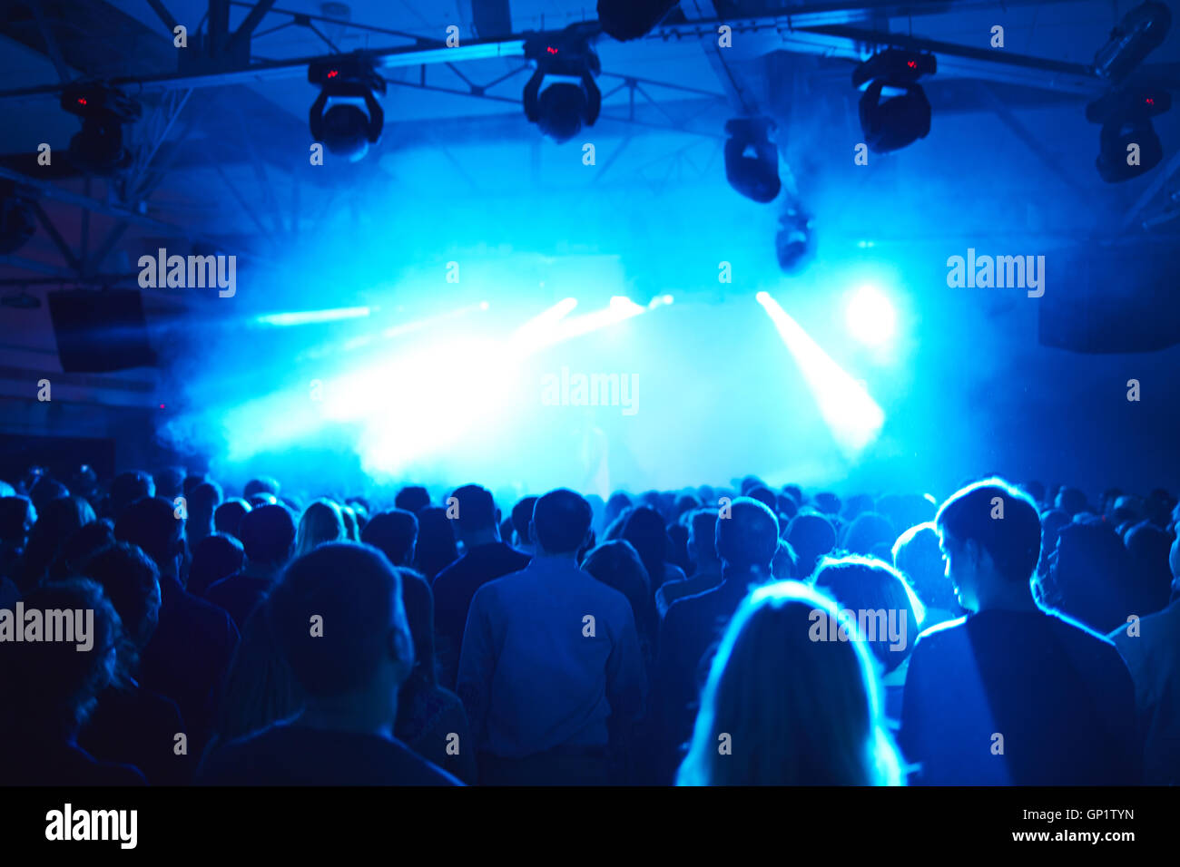 Rear view of large crowd of men and women standing motionless in dark ...