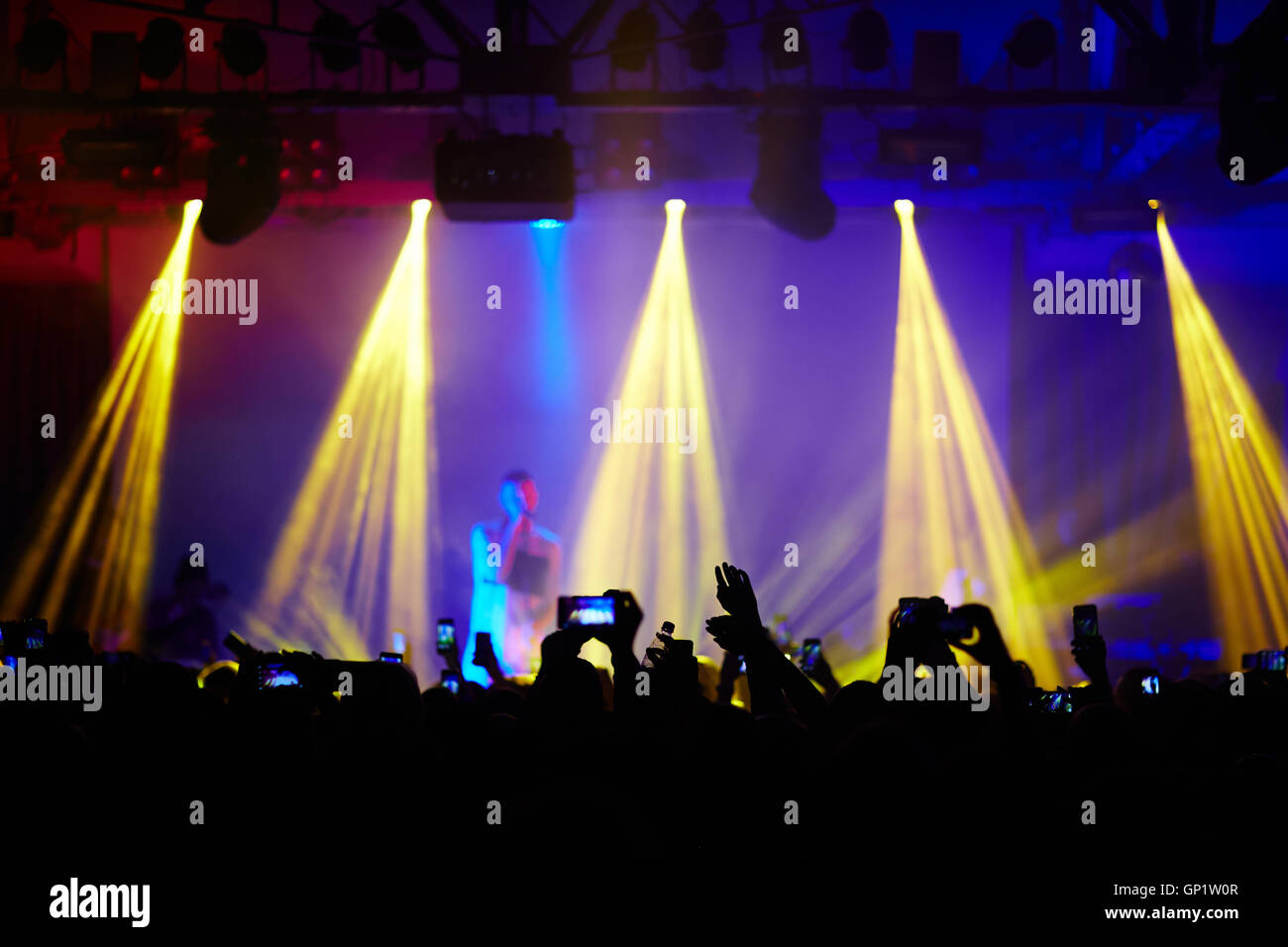 Fans in crowd raising hands up cheering in front of stage at music ...