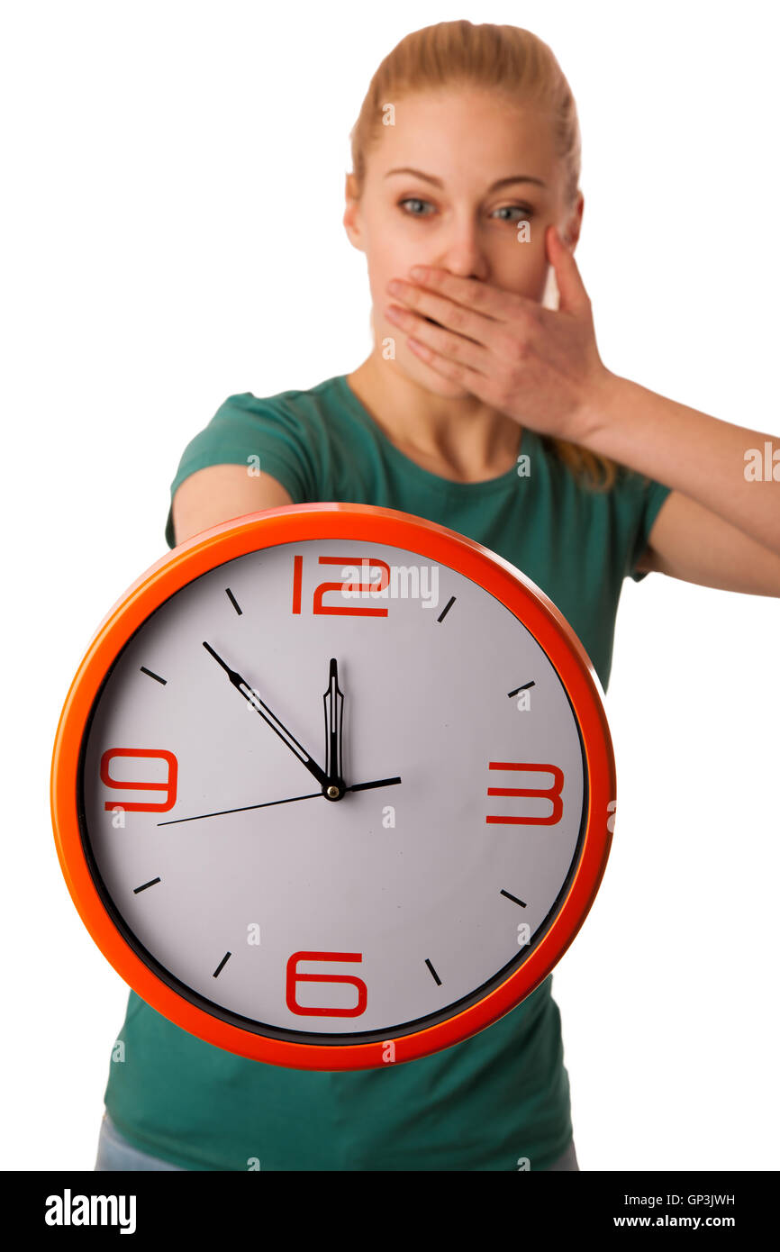 Blonde woman holding big clock in hand gesturing being late, isolated ...