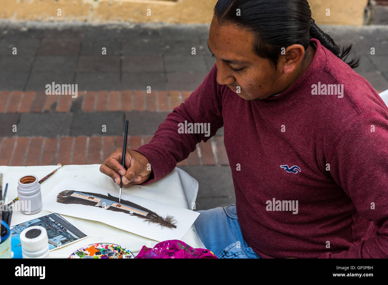 A local artist is creating hand painted feather art as souvenir. Quito ...