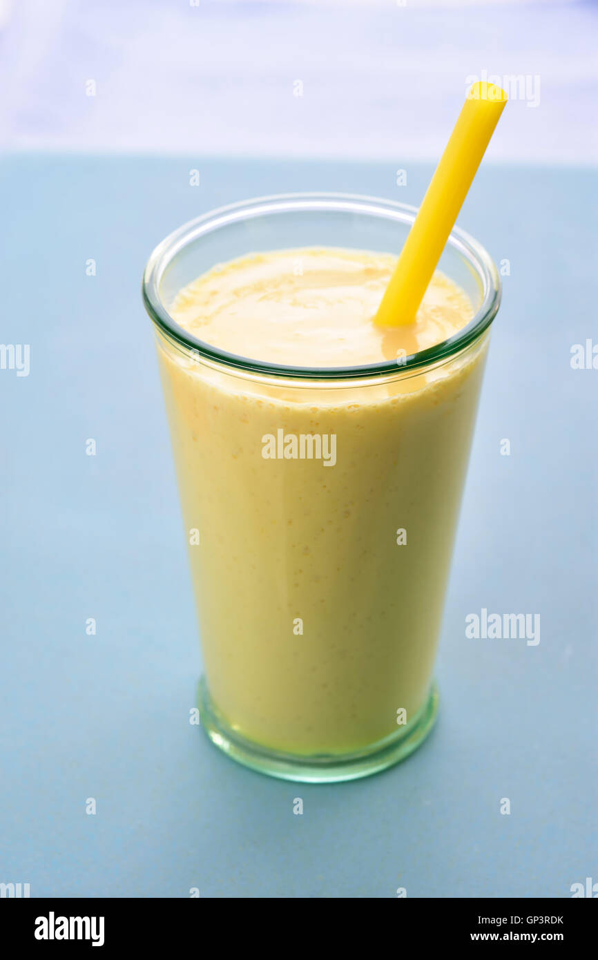 Mango lassi in glass with straw. Mango smoothie made with mango and ...