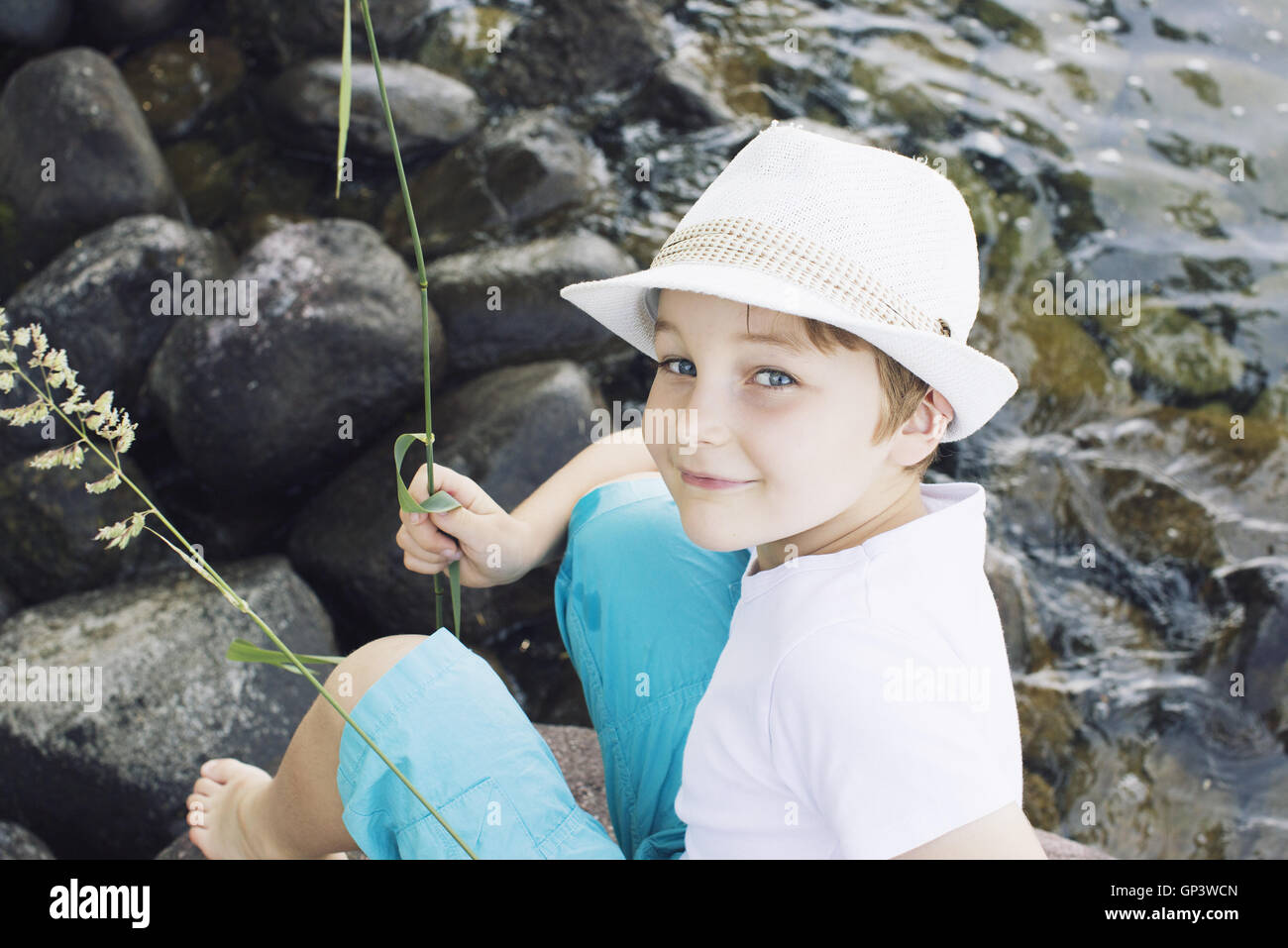 Boy sitting by stream Stock Photo - Alamy