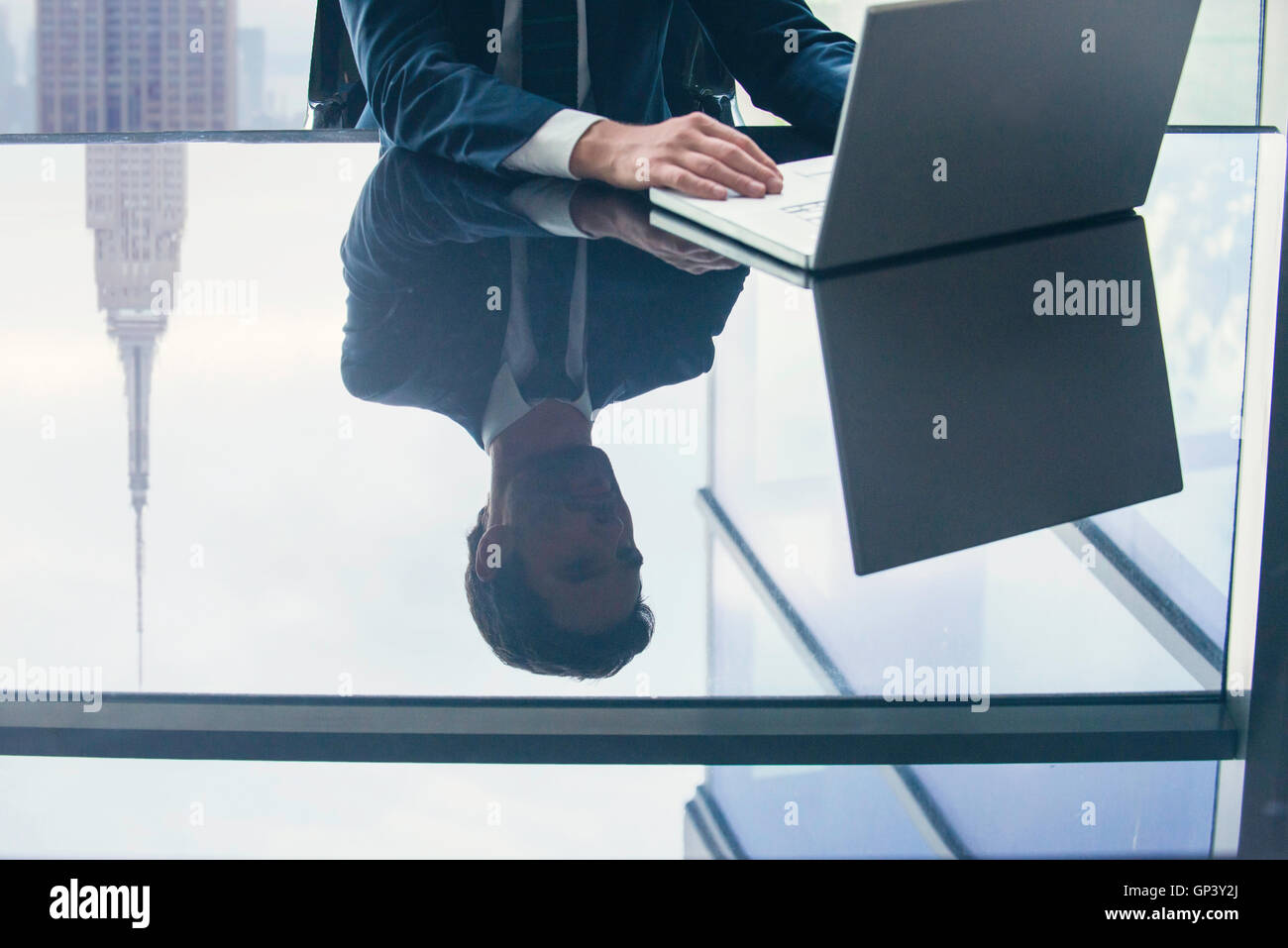 Businessman using laptop computer, reflection on glass top table Stock ...