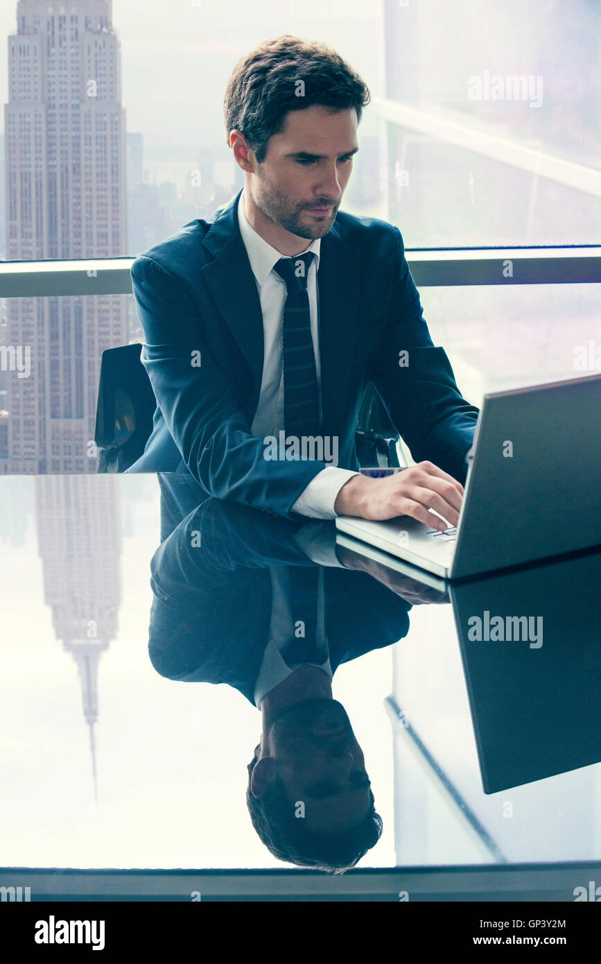 Businessman using laptop computer alone at conference table Stock Photo ...
