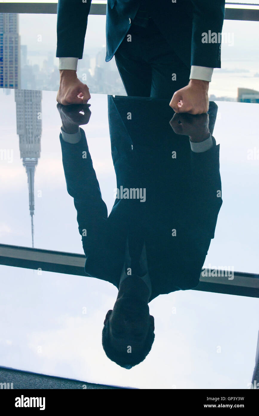 Businessman leaning against table, reflection on glass top Stock Photo ...
