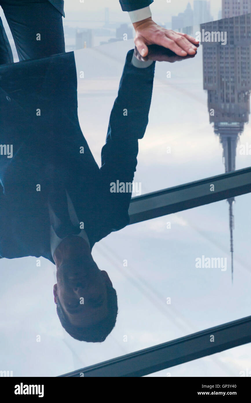 Businessman leaning against table, reflection in glass top Stock Photo ...