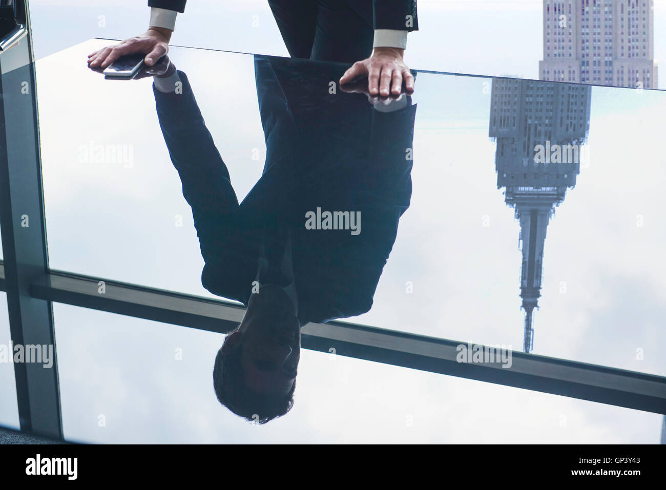 Businessman leaning against table, reflection in glass top Stock Photo ...