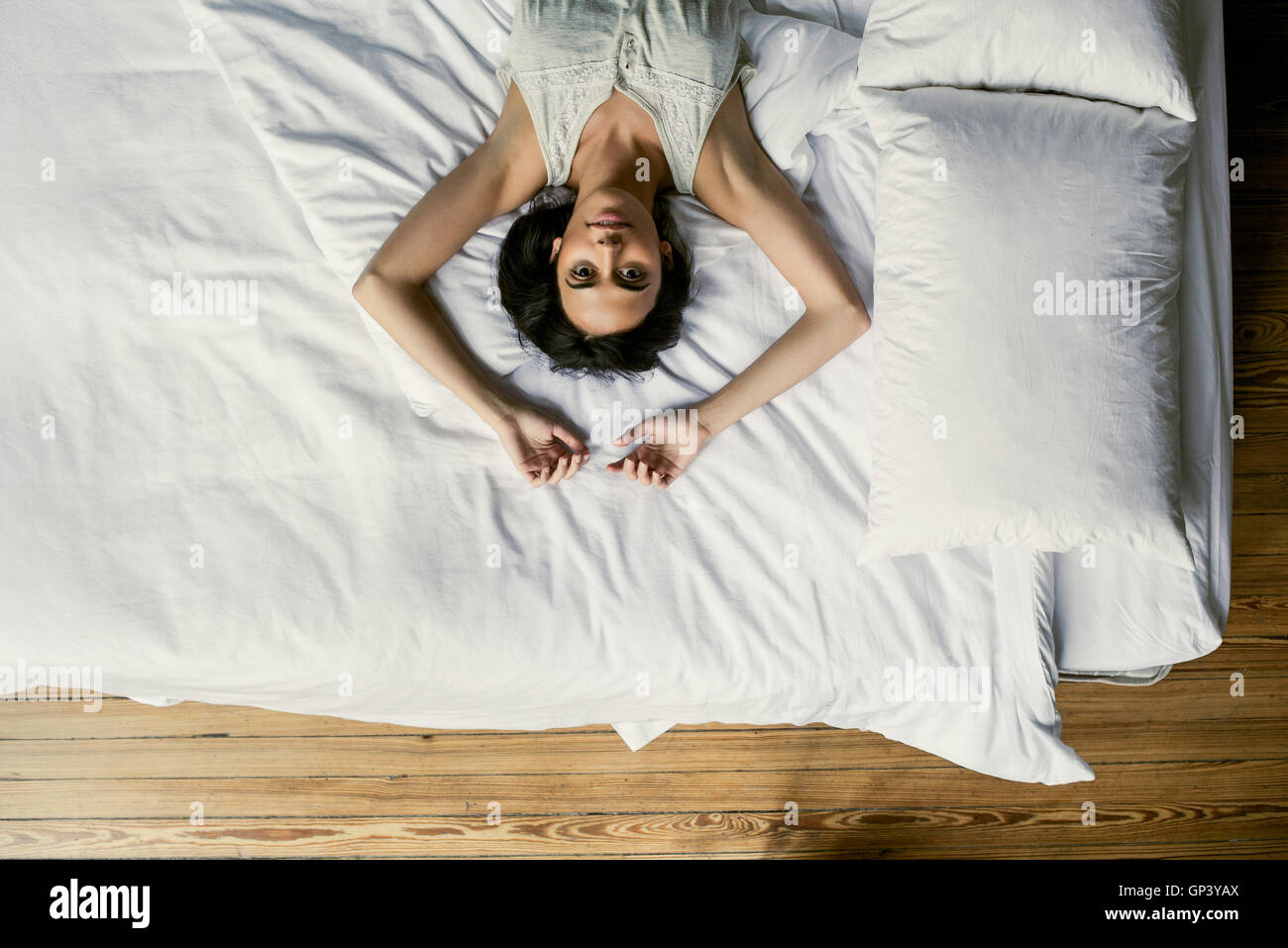 Woman lying in bed stretching Stock Photo - Alamy