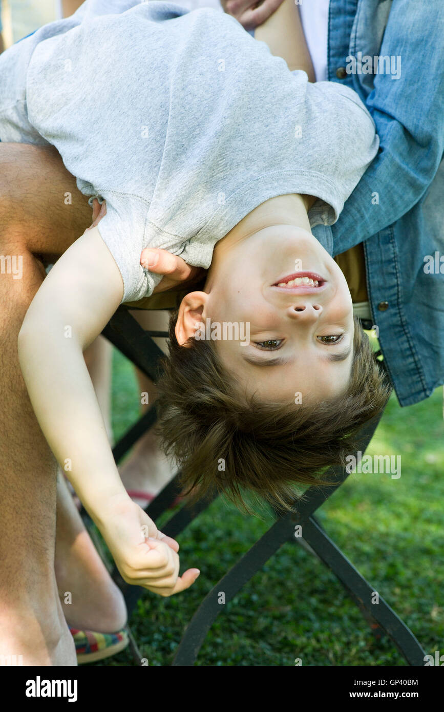 Little boy lying across father's lap hanging upside down Stock Photo ...