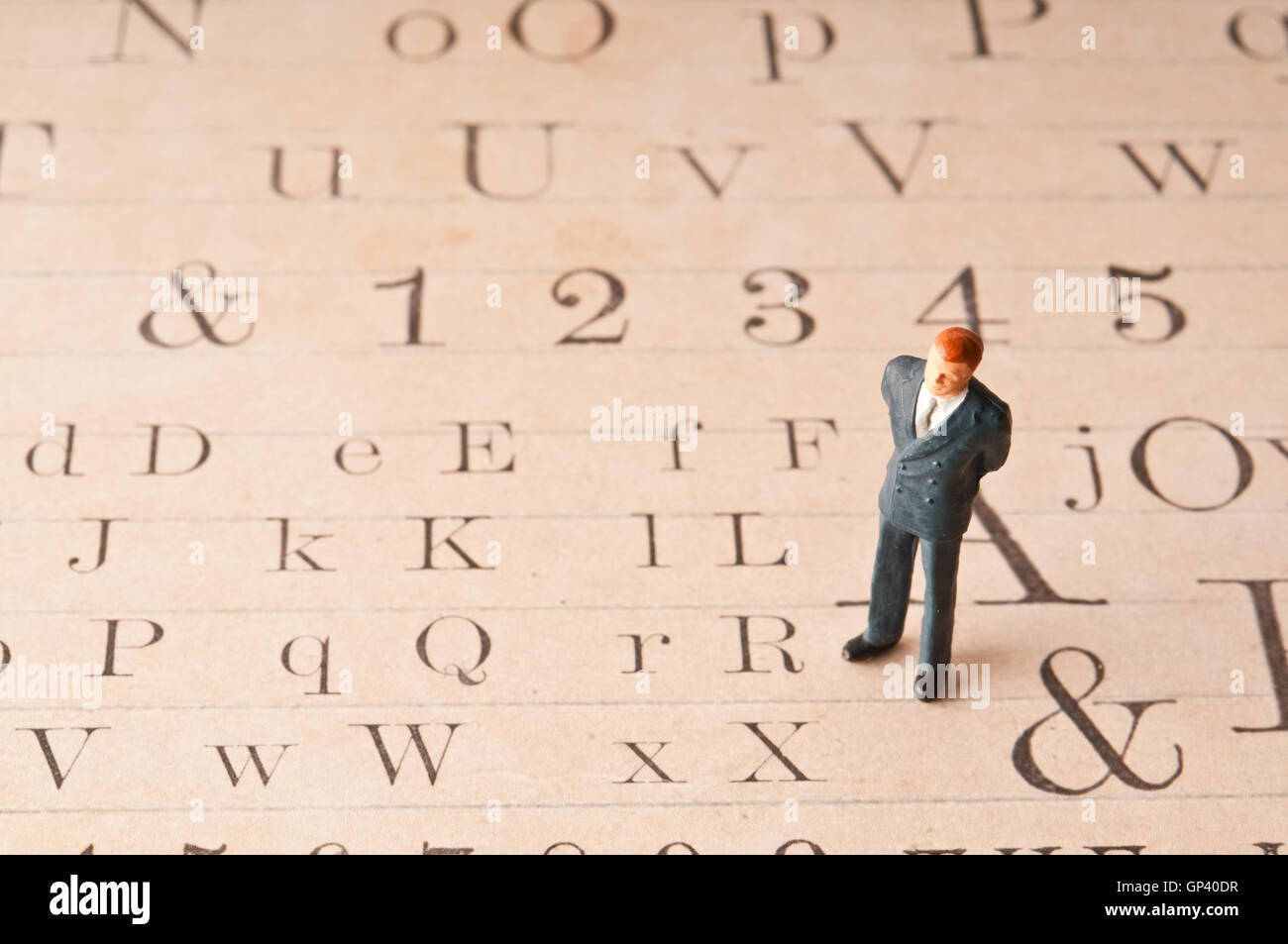 male miniature figurine standing on an alphabet page, literacy and ...