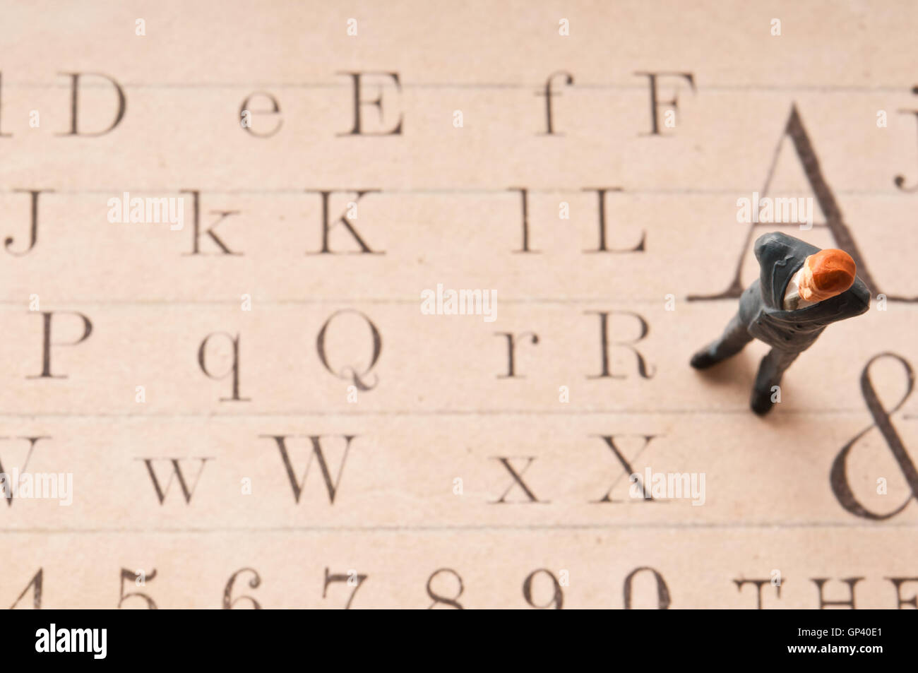 male miniature figurine standing on an alphabet page, literacy and ...