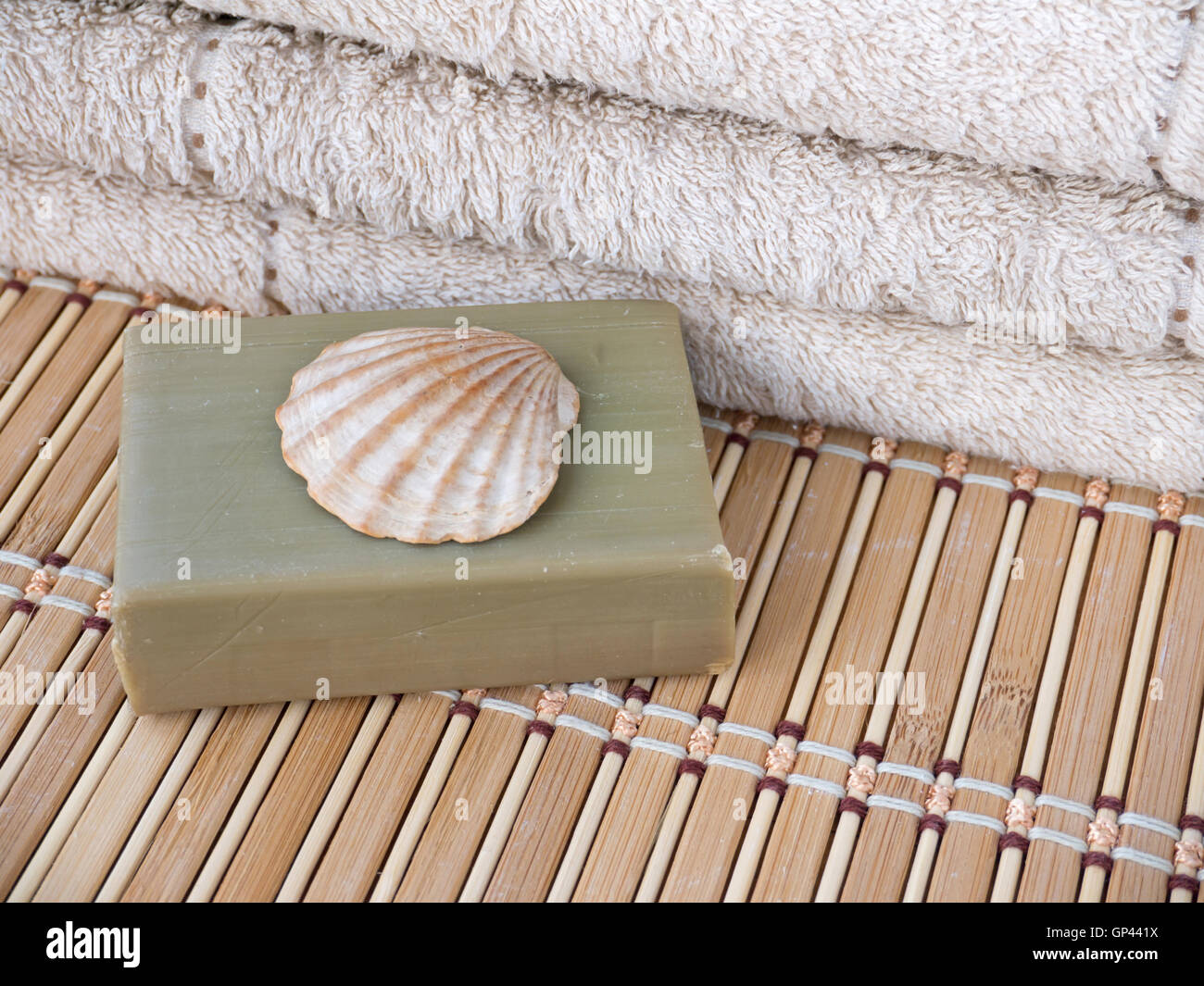 Natural olive soap bar, scallop shell and terry towel on the bamboo mat ...