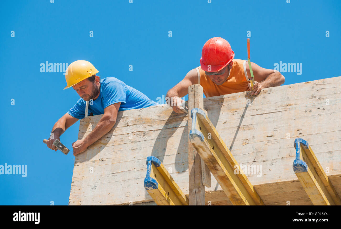 Construction workers nailing cement formwork in place Stock Photo - Alamy