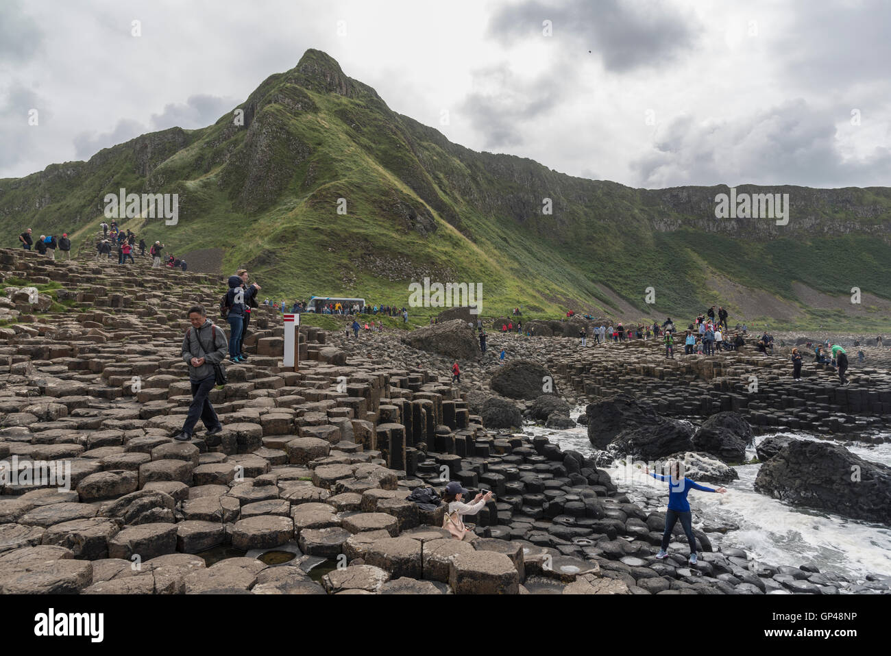 People walk around Giant's Causeway with hills in the background Stock ...