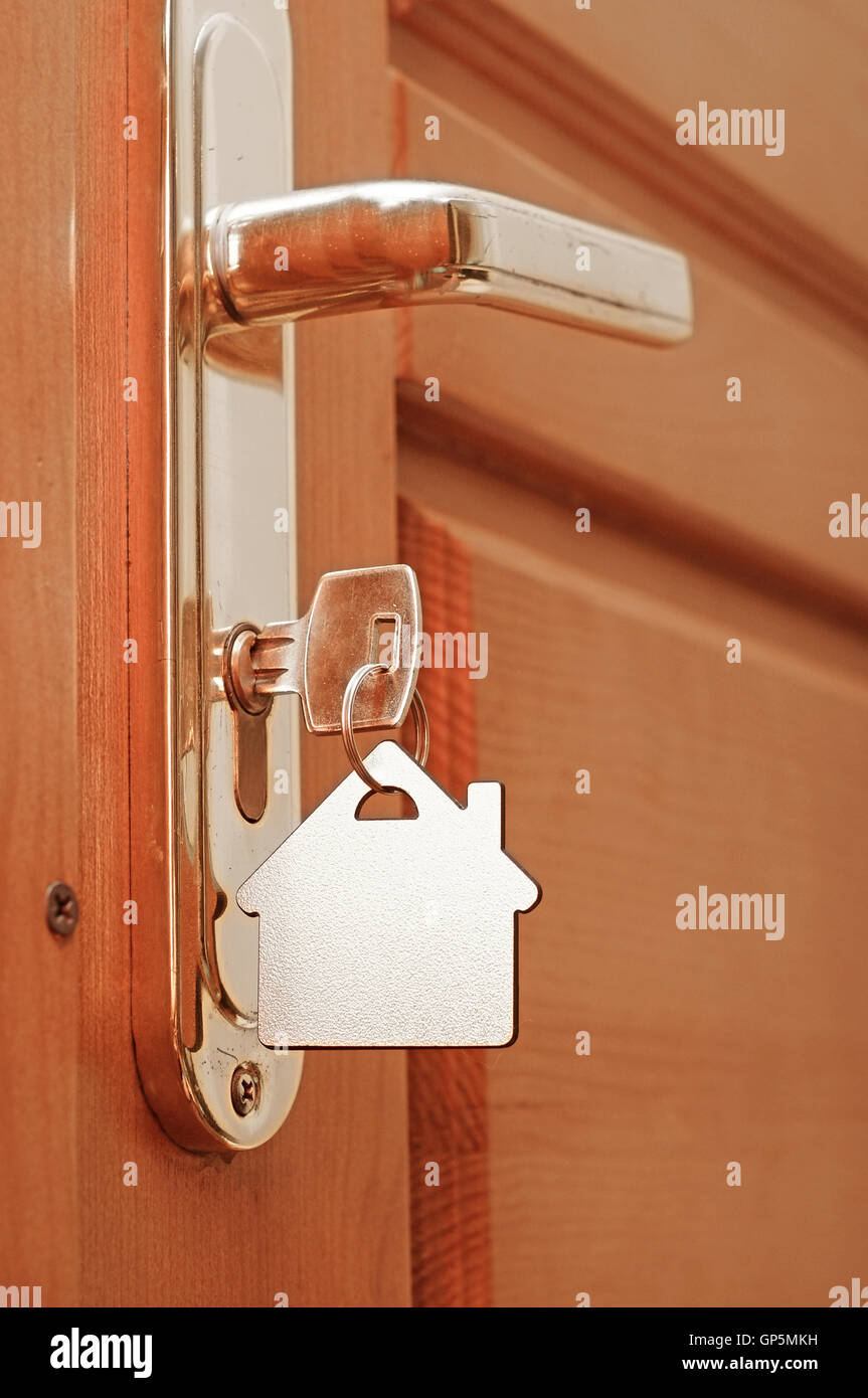 House key on a house shaped keyring in the lock of a door Stock Photo ...