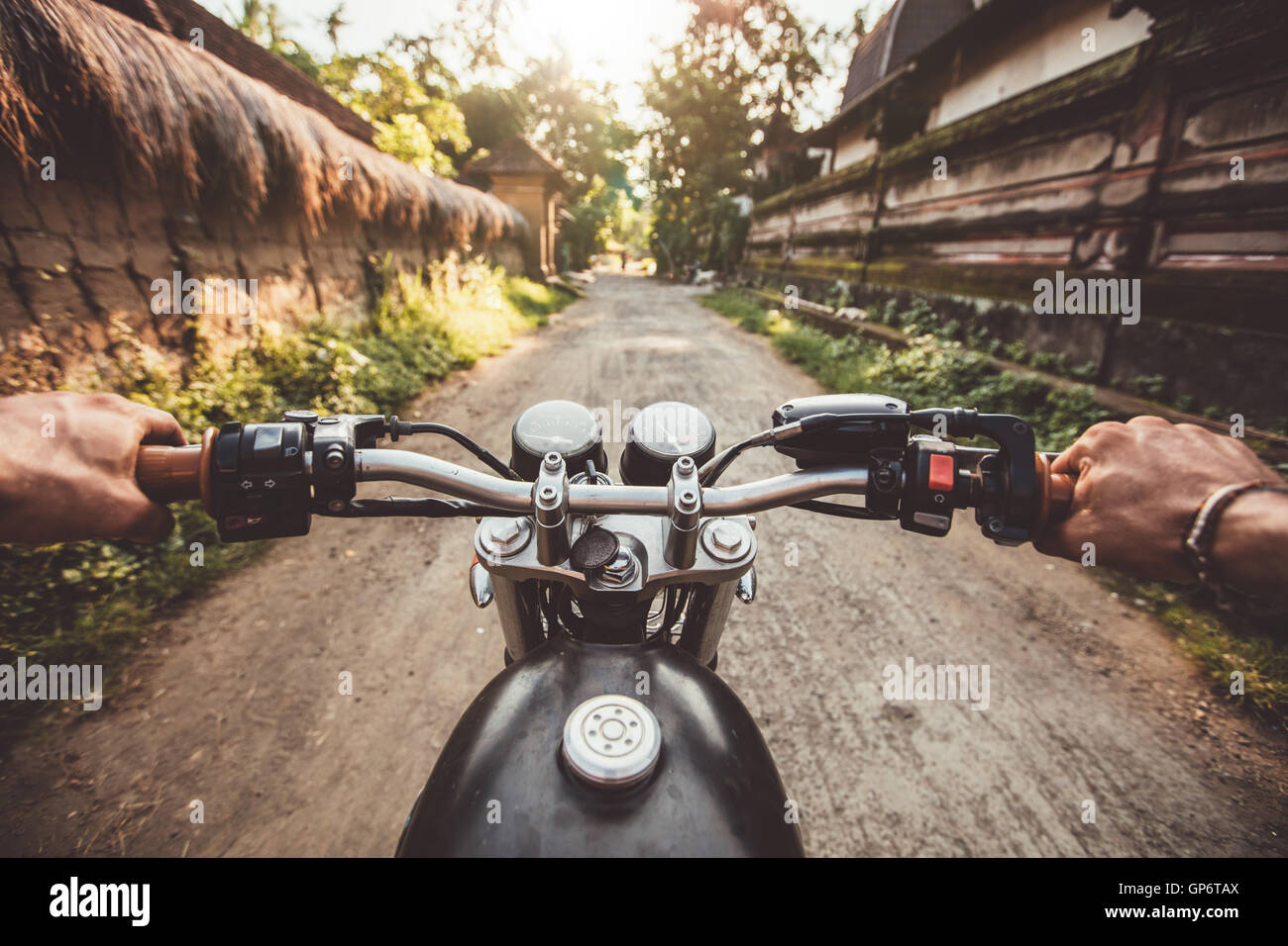 Biker driving his motorcycle on country road in a village. Point of ...