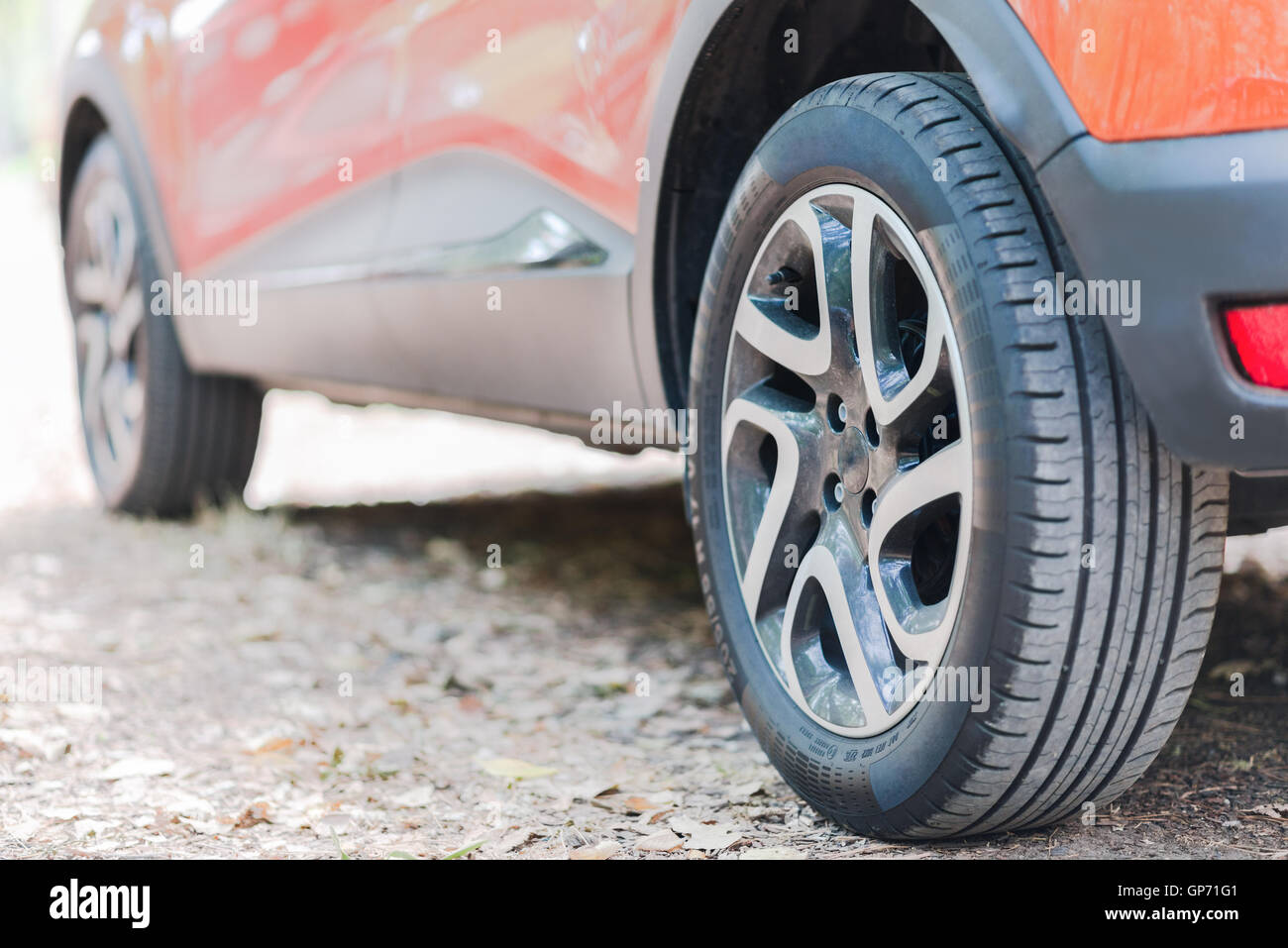 Close up of car tyres. Back view of a parked car over a road covered ...
