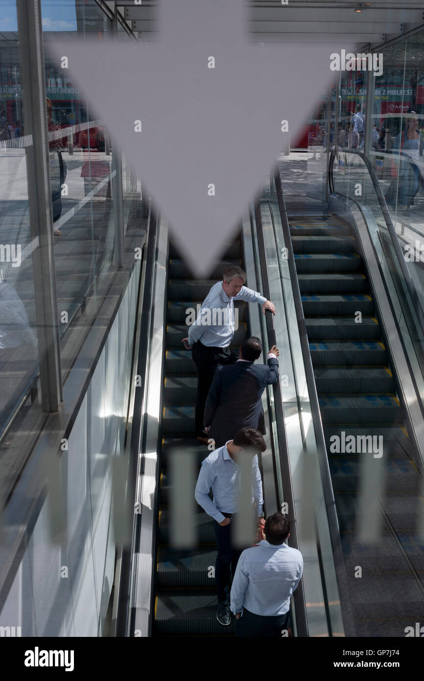 A down arrow and underground travellers who descend by escalator in ...