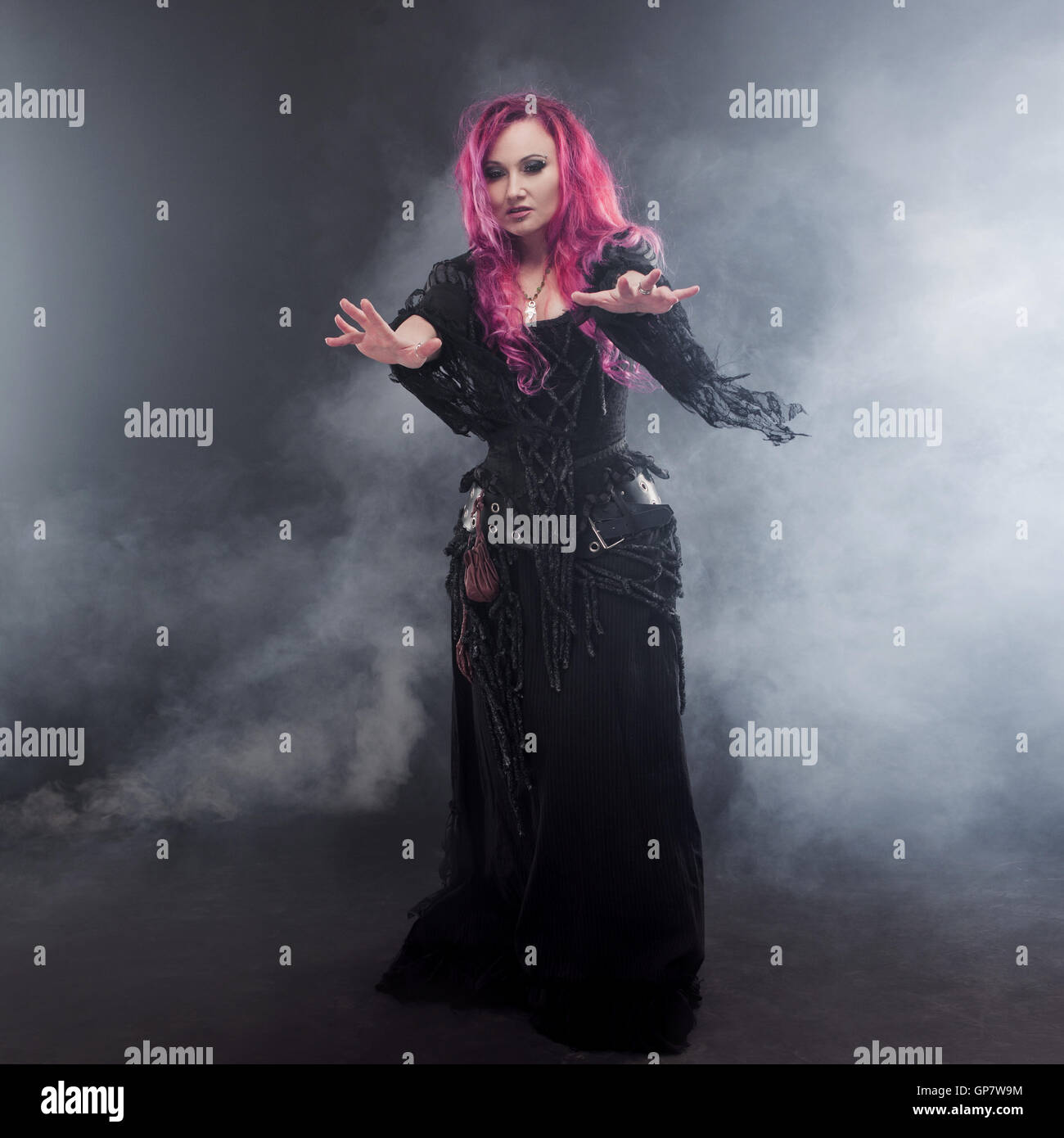 Halloween Witch creates magic. Attractive woman with red hair in ...