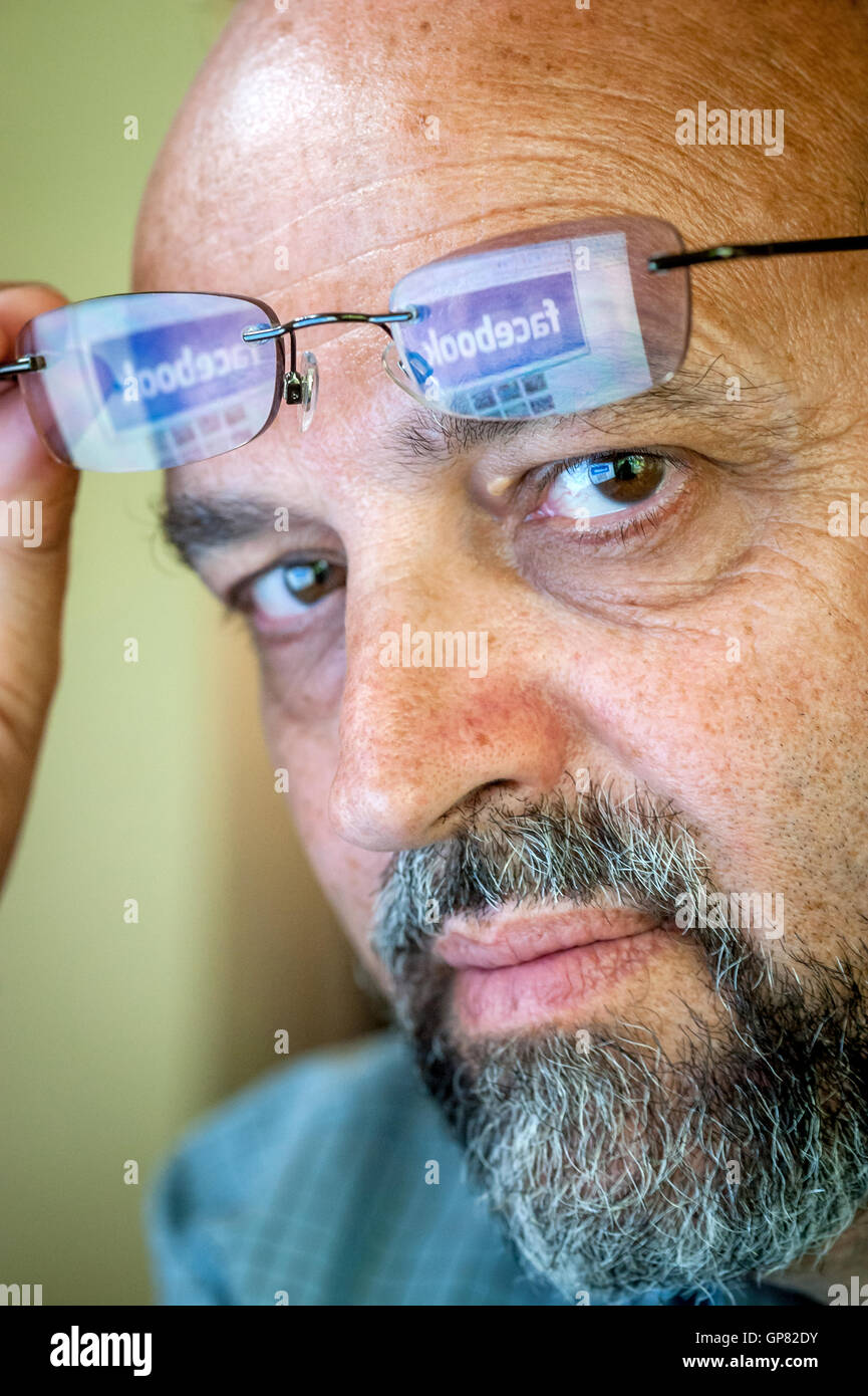 The Facebook logo reflected in a man's eyes and glasses Stock Photo - Alamy