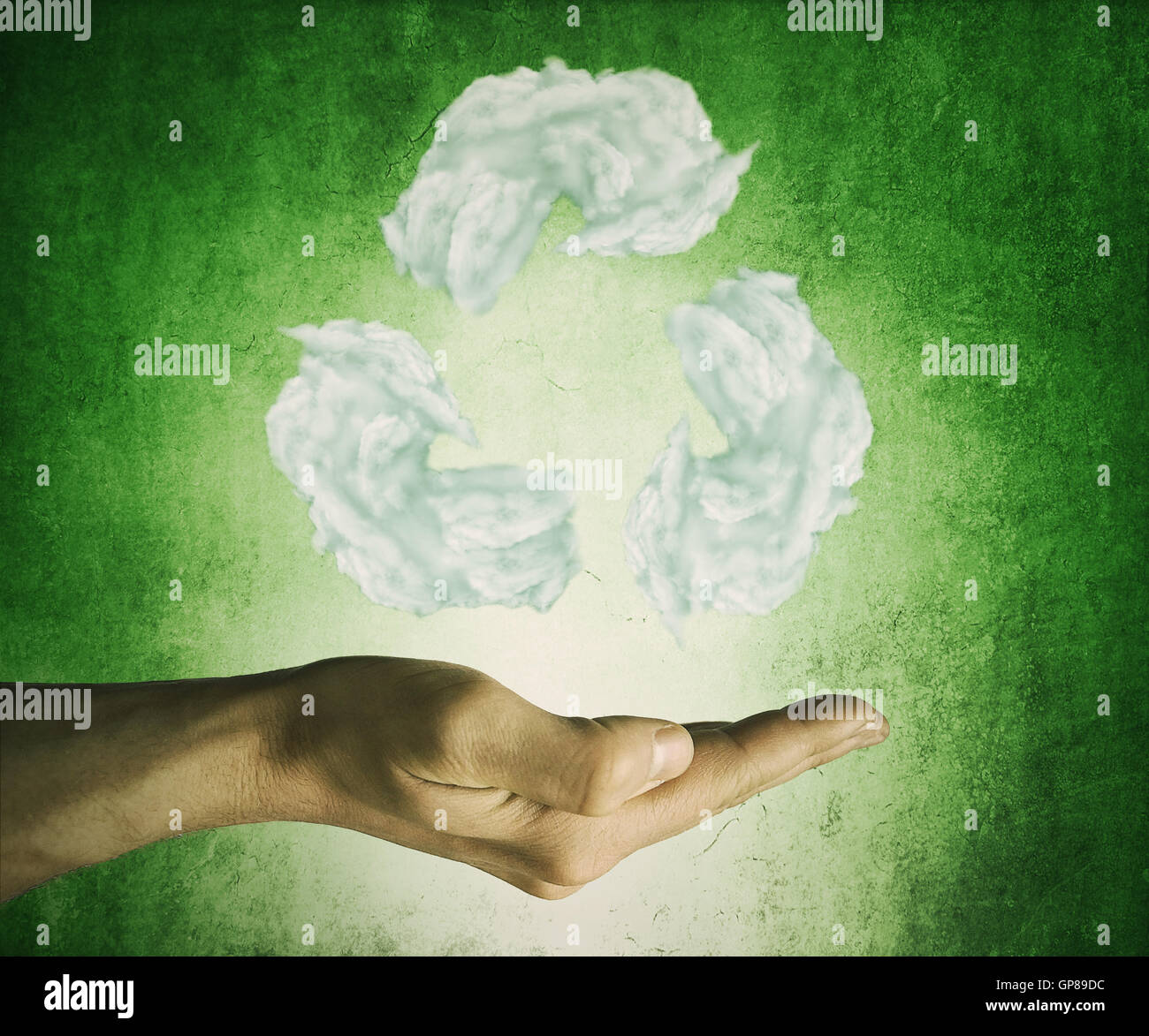 Opened hand holding recycling symbol from clouds on a green background ...
