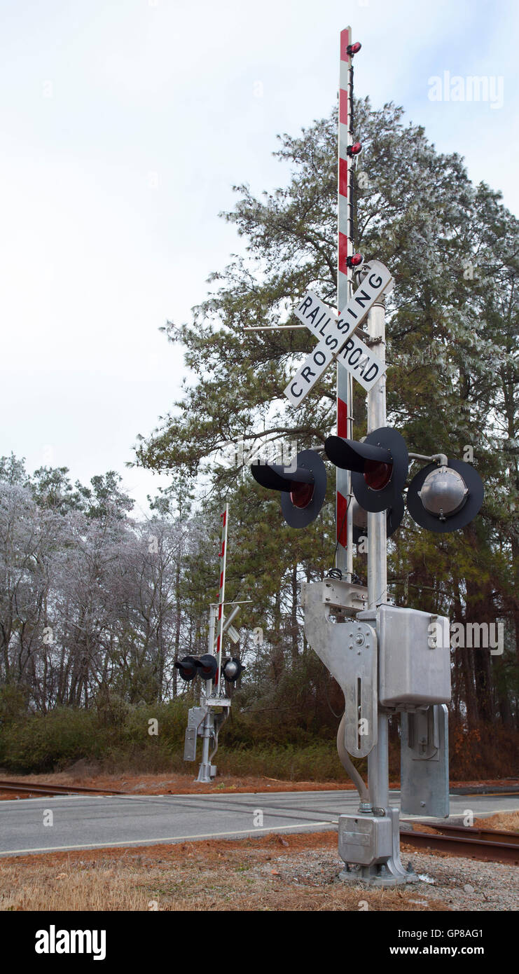 Pair of railroad crossing markers on a small road with trees alongside ...