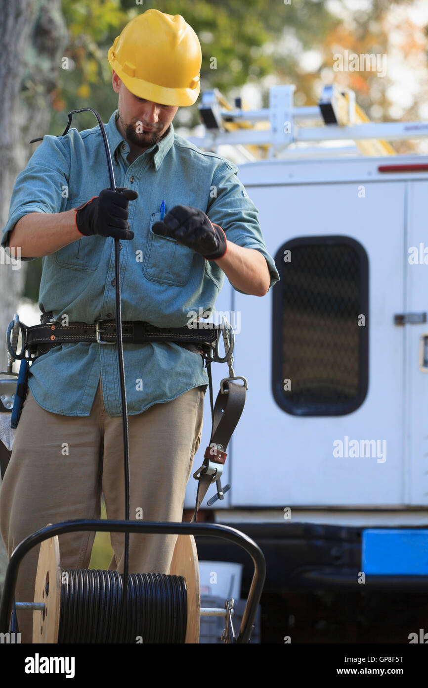 Cable lineman pulling cable from reel at site Stock Photo - Alamy
